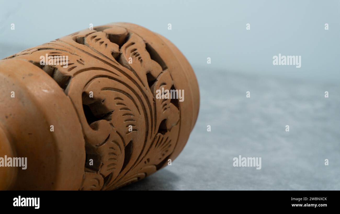 A clay jug with reliefs on the sides is placed on a gray table with a ...