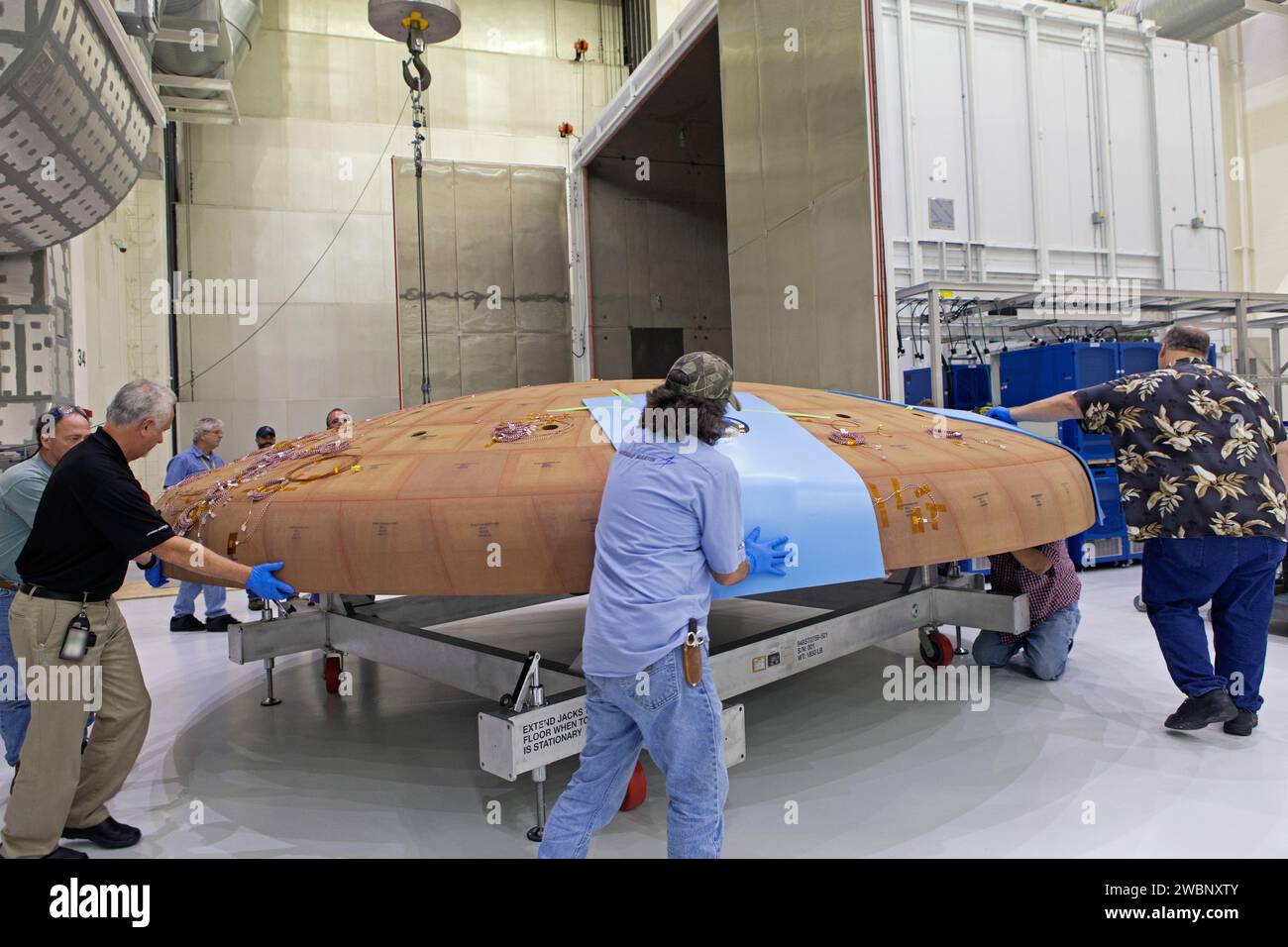 Technicians move the Orion heat shield for Artemis I toward the thermal ...