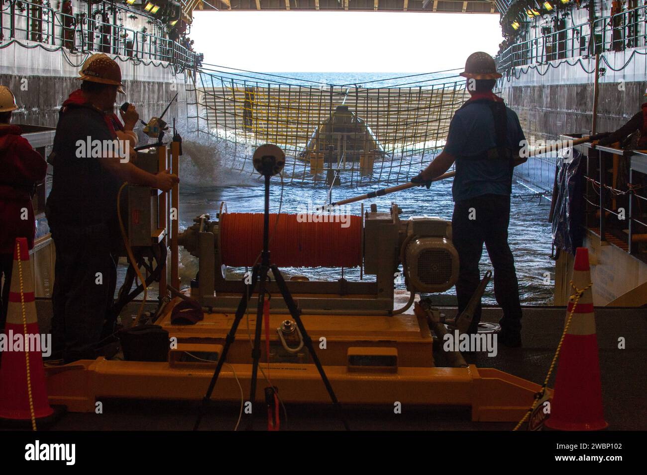 Winch team operators guide a test Orion crew module into the flooded ...