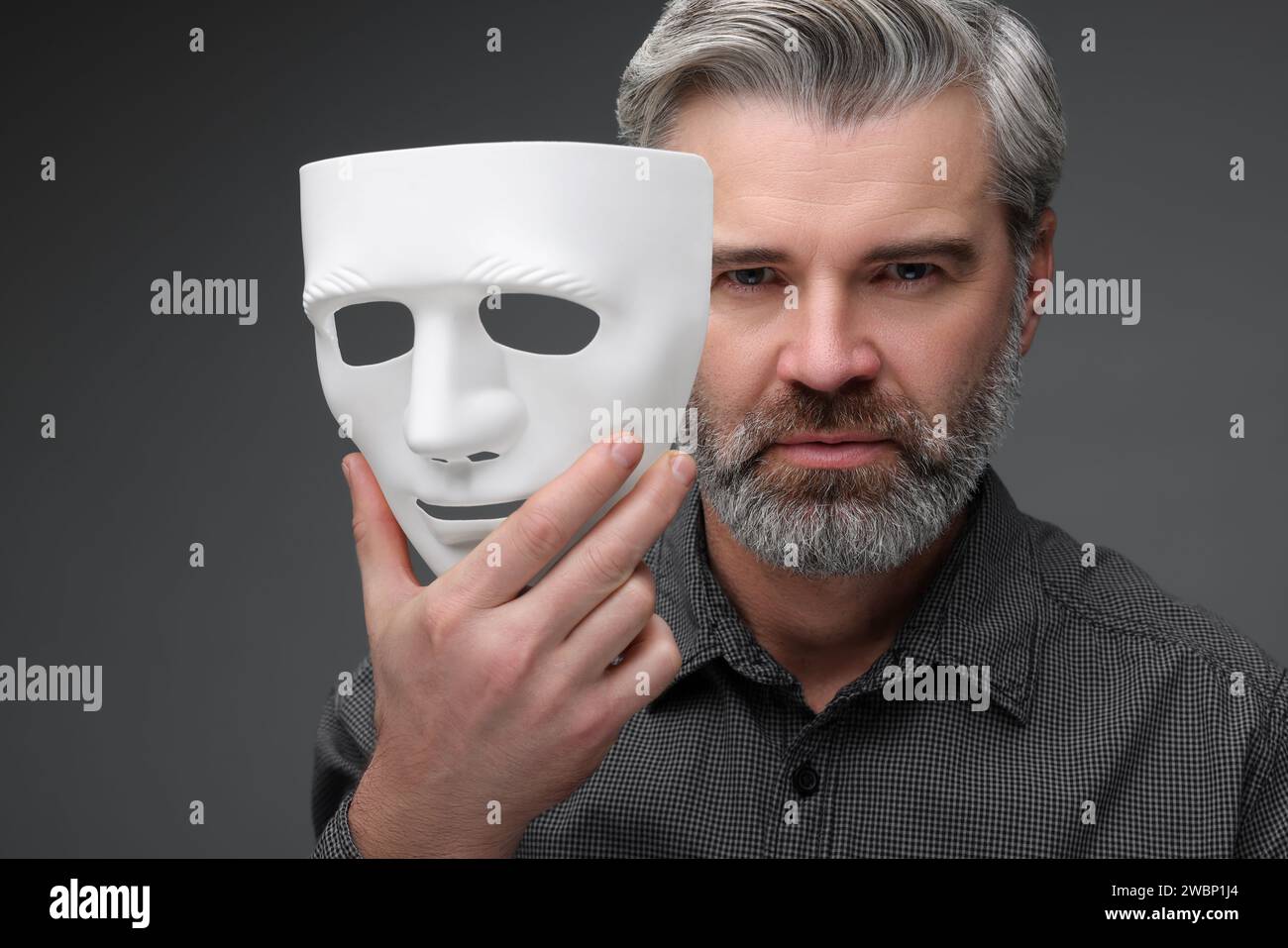 Multiple personality concept. Man with mask on dark grey background ...