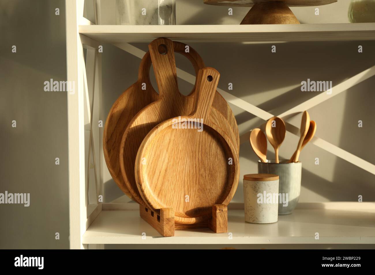 Wooden cutting boards and kitchen utensils on shelving unit Stock Photo ...