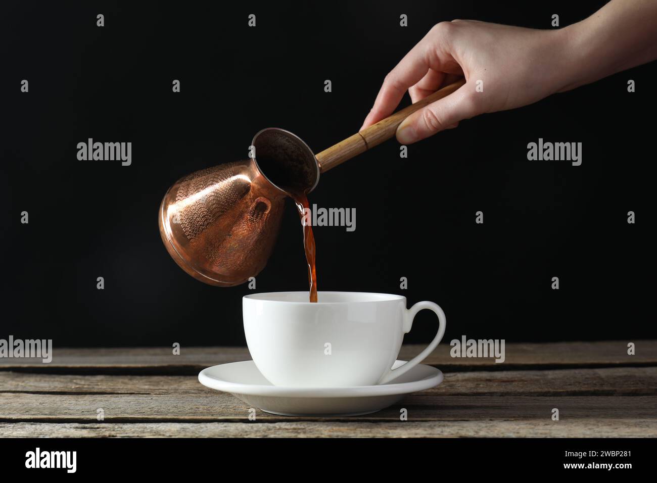 Turkish coffee. Woman pouring brewed beverage from cezve into cup at ...