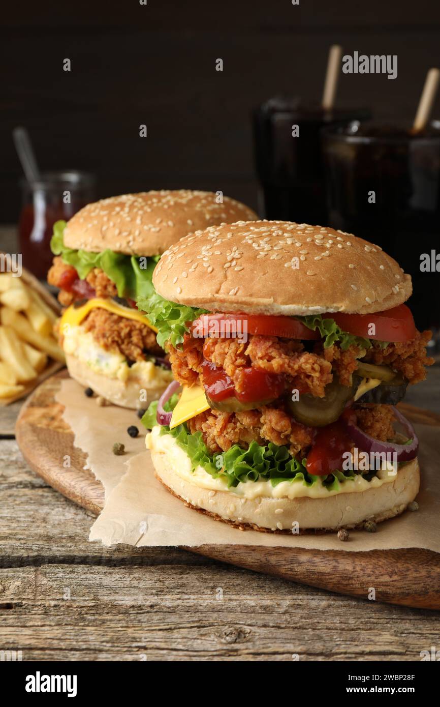 Delicious burgers with crispy chicken patty on wooden table Stock Photo ...