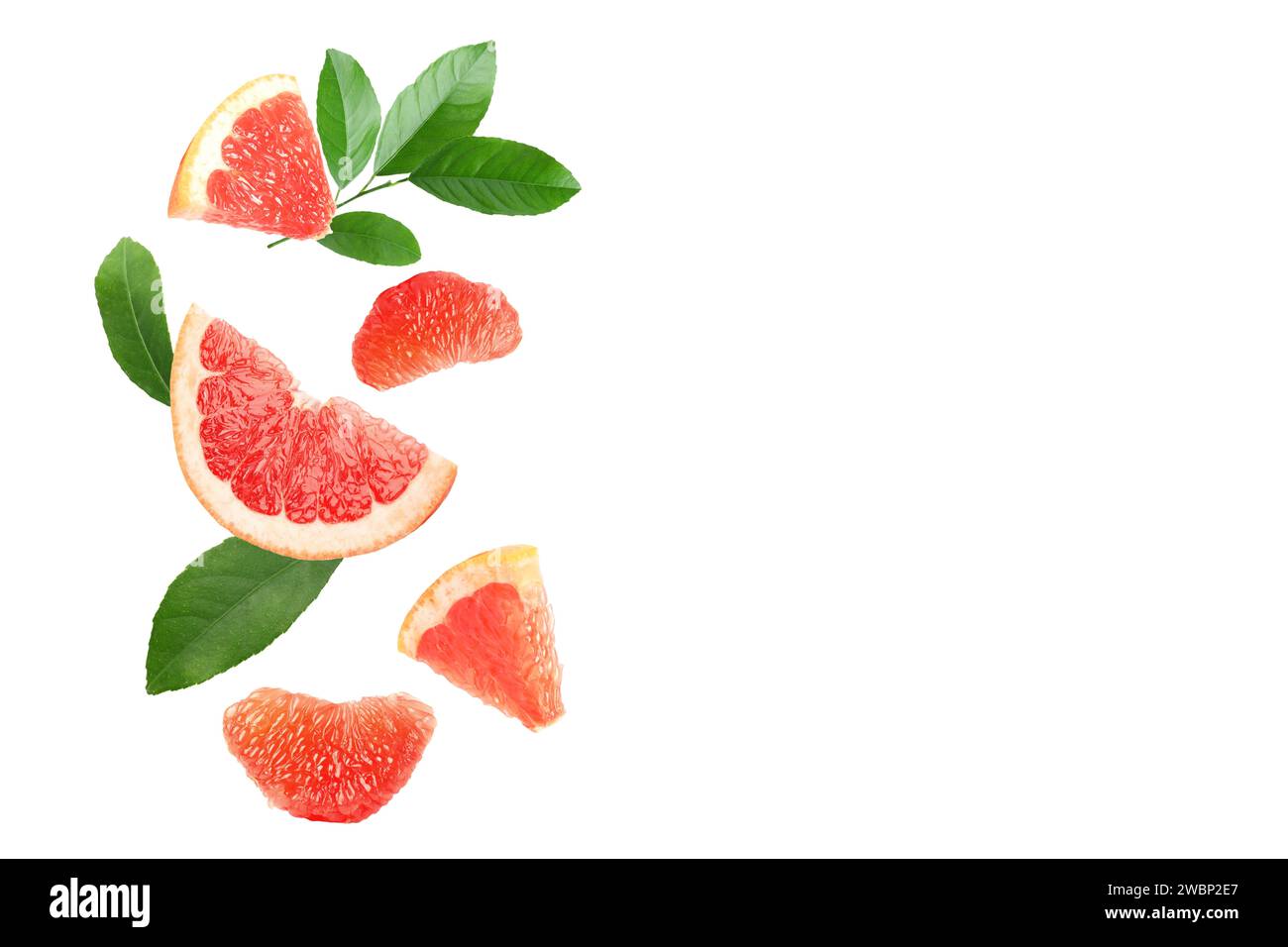 Fresh grapefruit pieces and green leaves falling on white background ...