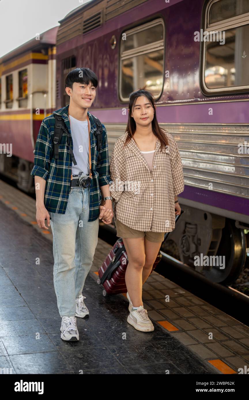 Young happy Asian couple travelers are commuting by train together ...