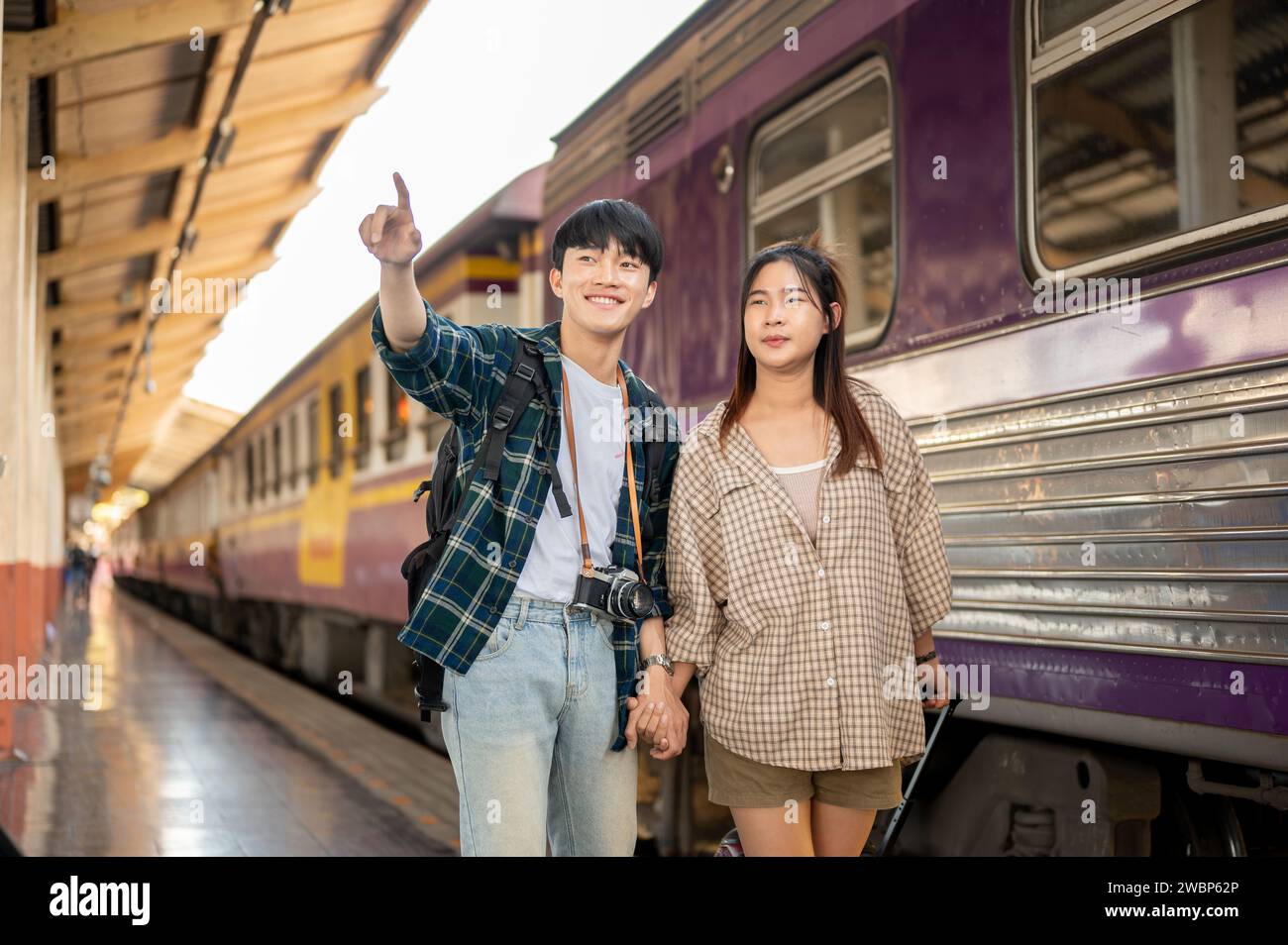Young happy Asian couple travelers are commuting by train together ...