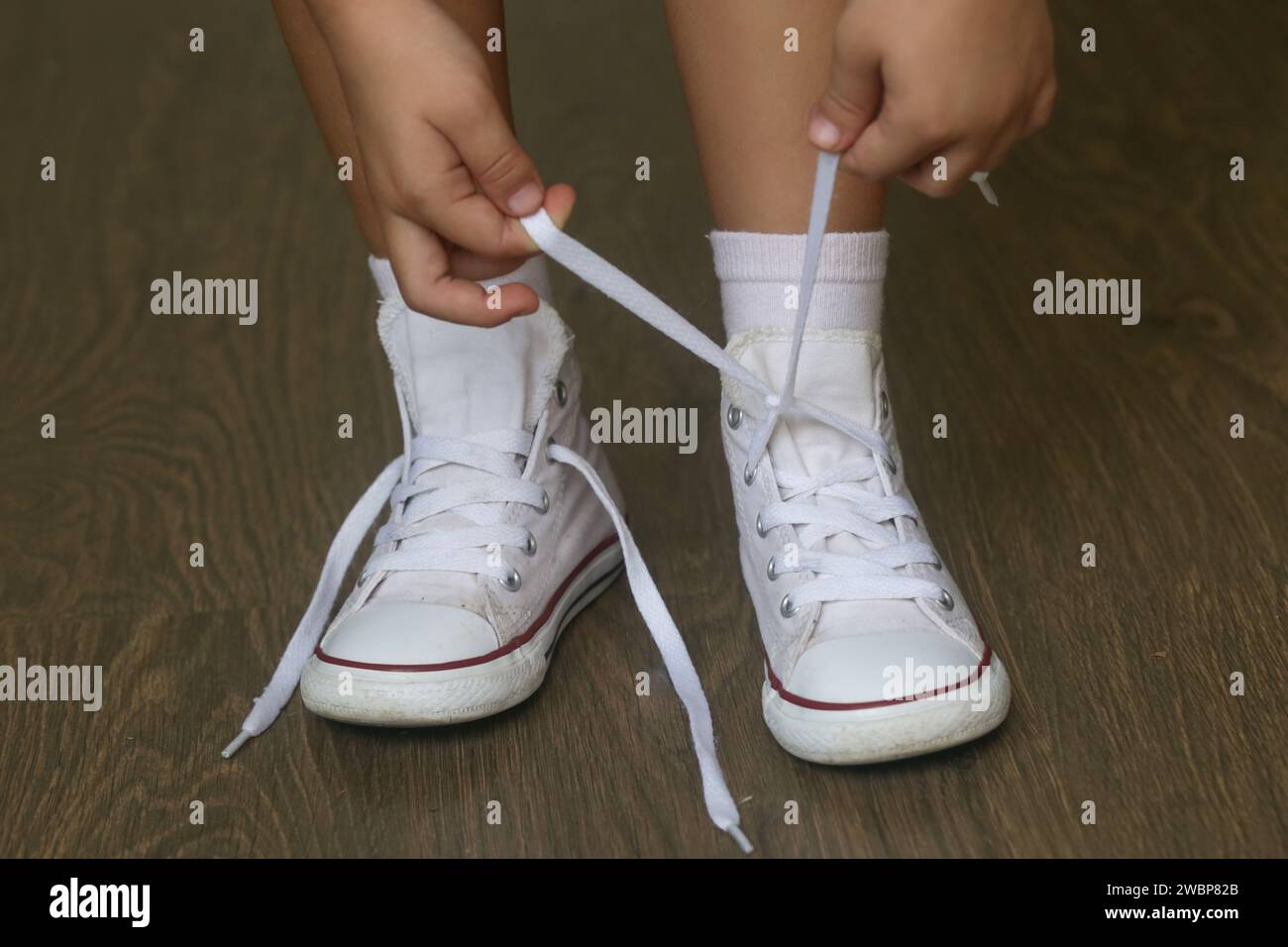 Kid tying shoes. Little girl struggling to tie shoe laces. Child learning fine motor skills ...
