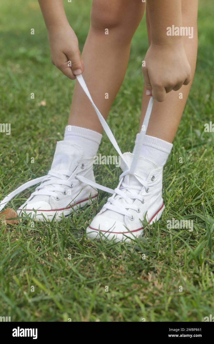 Kid tying shoes. Little girl struggling to tie shoe laces. Child learning fine motor skills ...