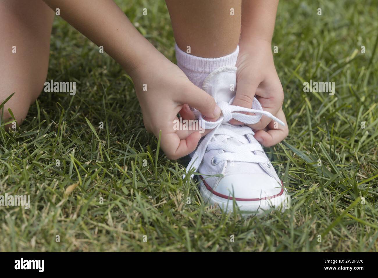 Kid tying shoes. Little girl struggling to tie shoe laces. Child learning fine motor skills ...