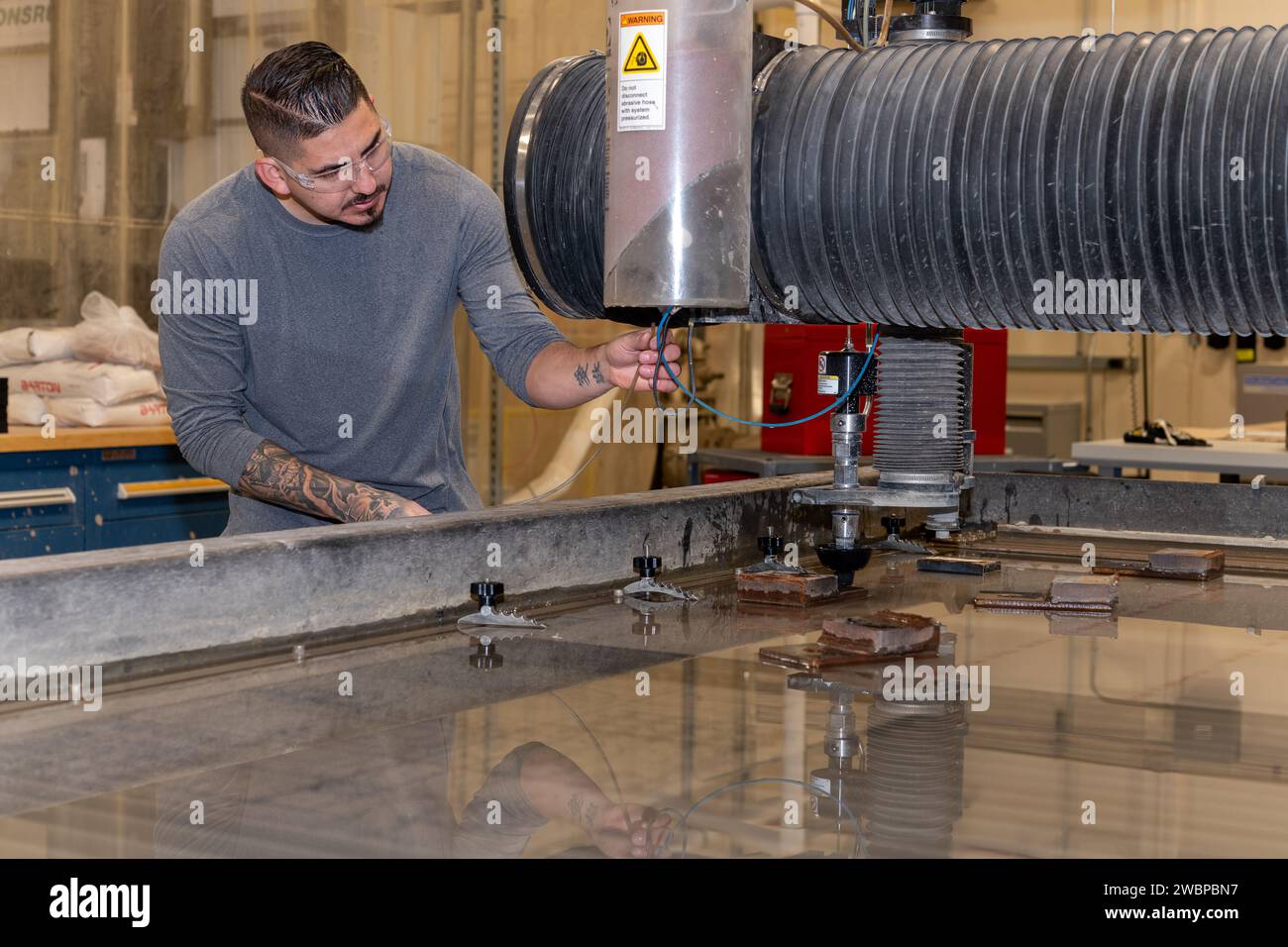 Matthew Sanchez uses a water jet to cut aluminum for the outer layer of ...