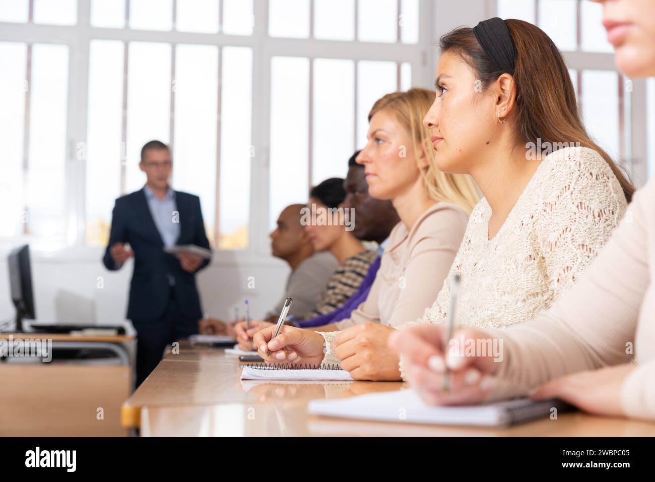 Side view of student group working on lecture in classroom, making ...