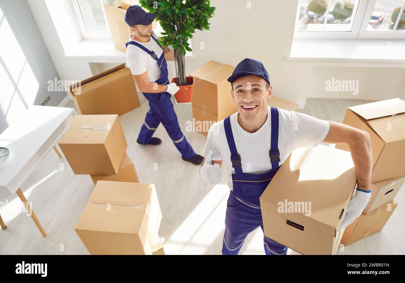 Happy employee of moving service standing in new house holding ...