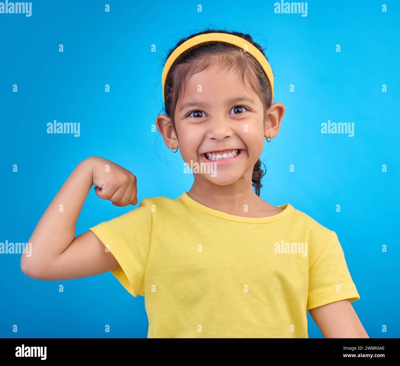 Strong, happy and portrait of a child with muscle isolated on a blue ...