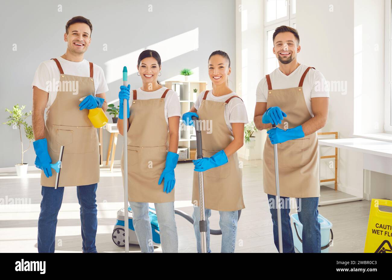 Happy janitors in uniform from professional cleaning service looking at ...
