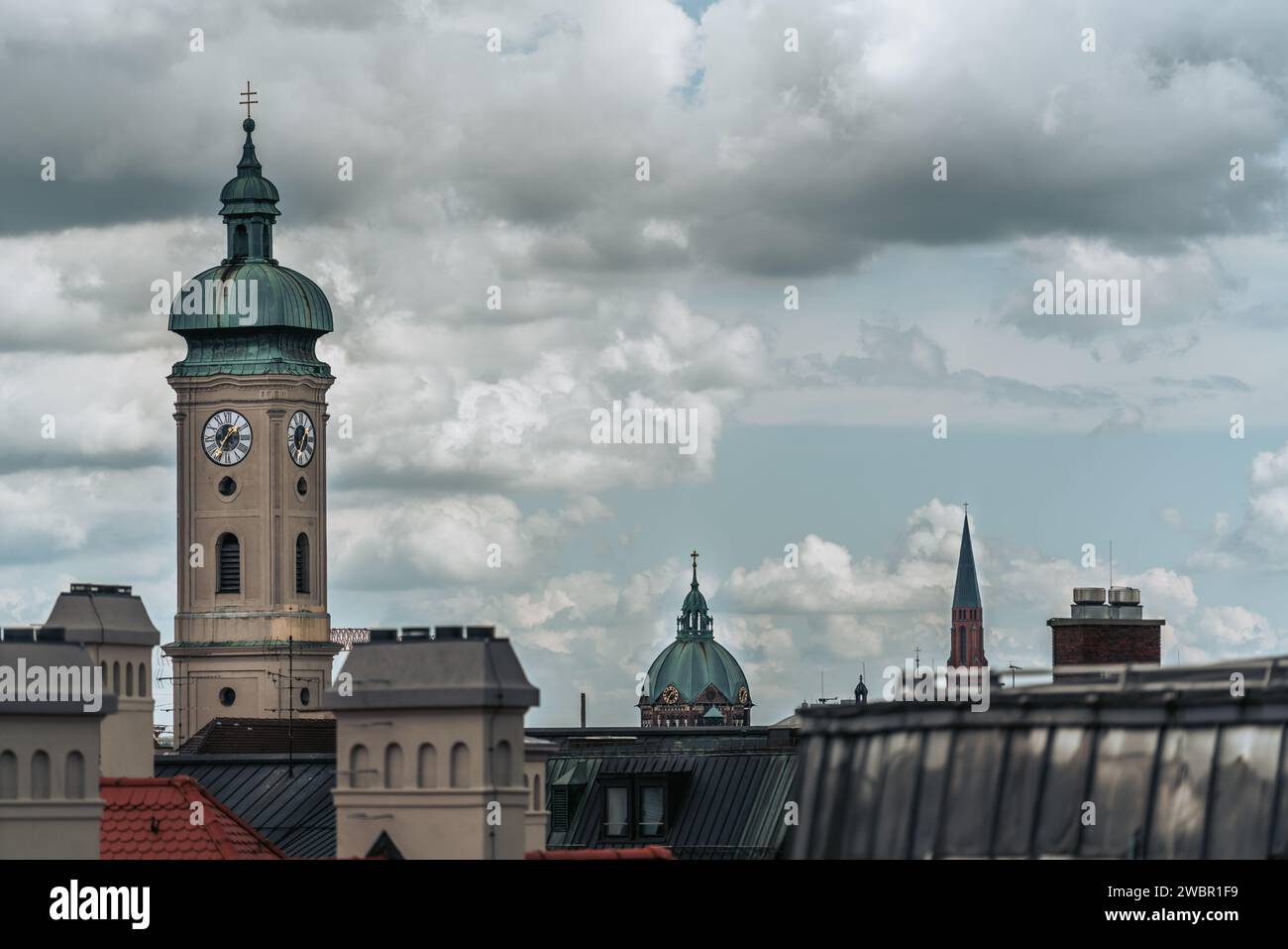 A clock tower against buildings on a cloudy day in Munich, Germany ...