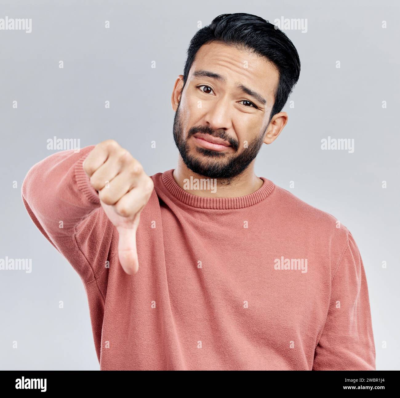 Sad, disappointment and portrait of an Asian man with a thumbs down ...