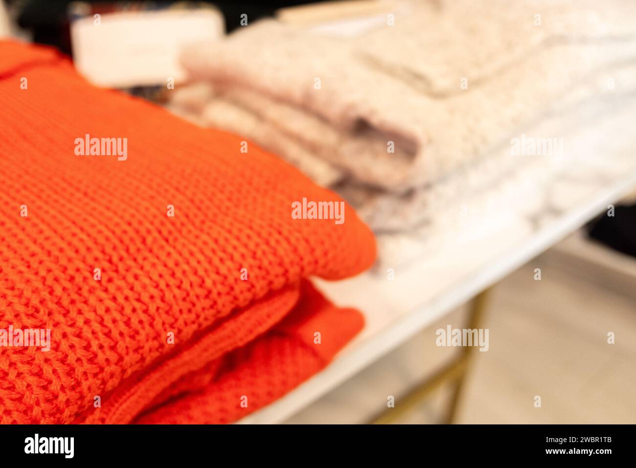 selective focus, red white wool sweaters folded on a clothing store ...