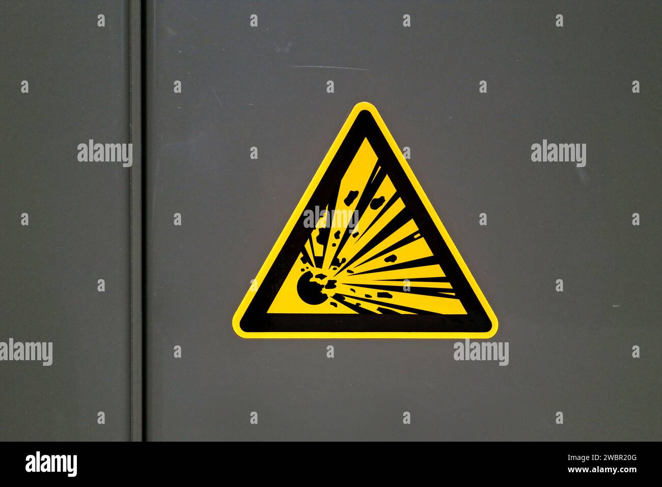 Yellow caution sign on a metal door warning about "Explosive Stock ...