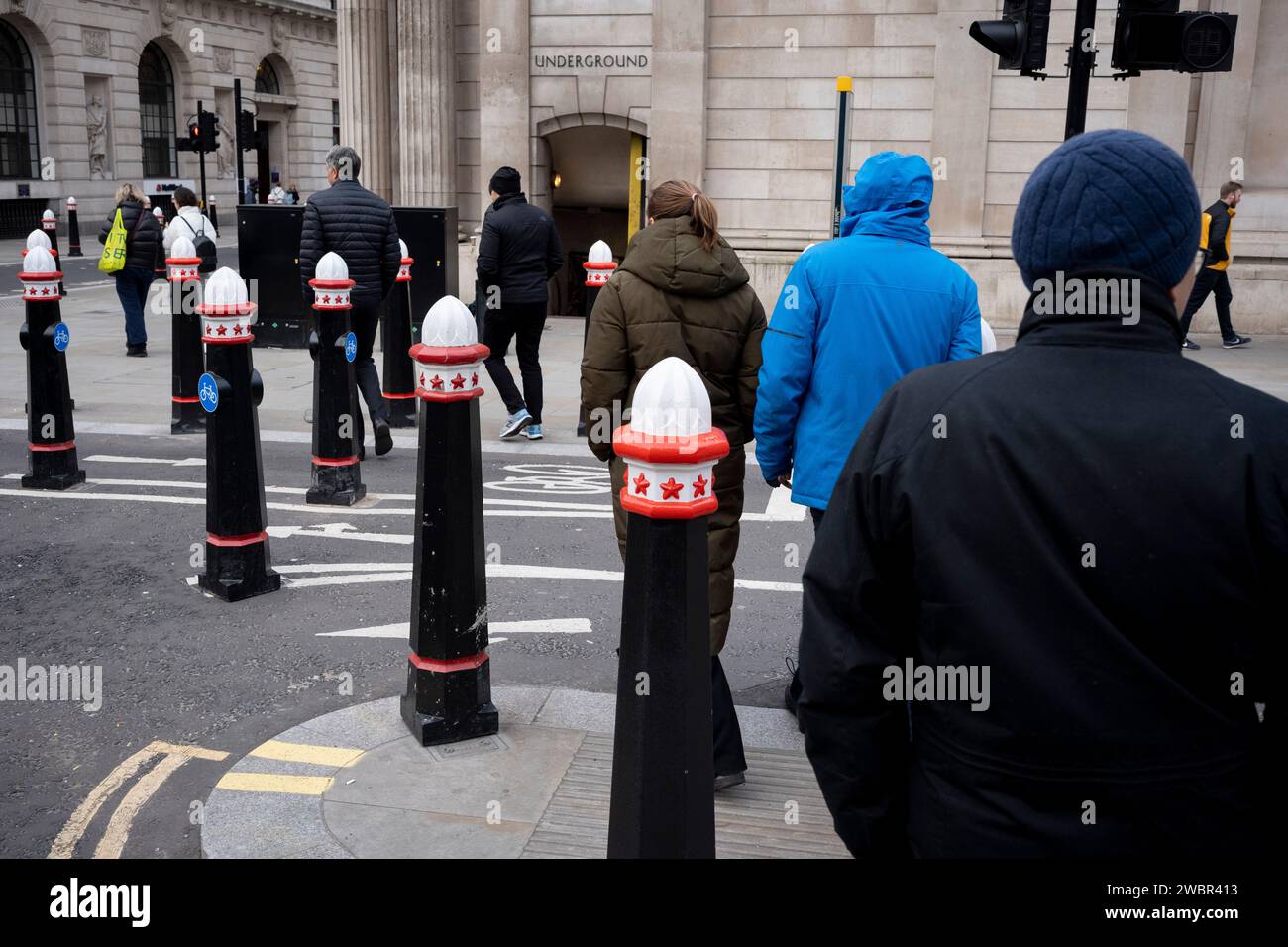 City workers walk past new street bollards after a widening of the ...