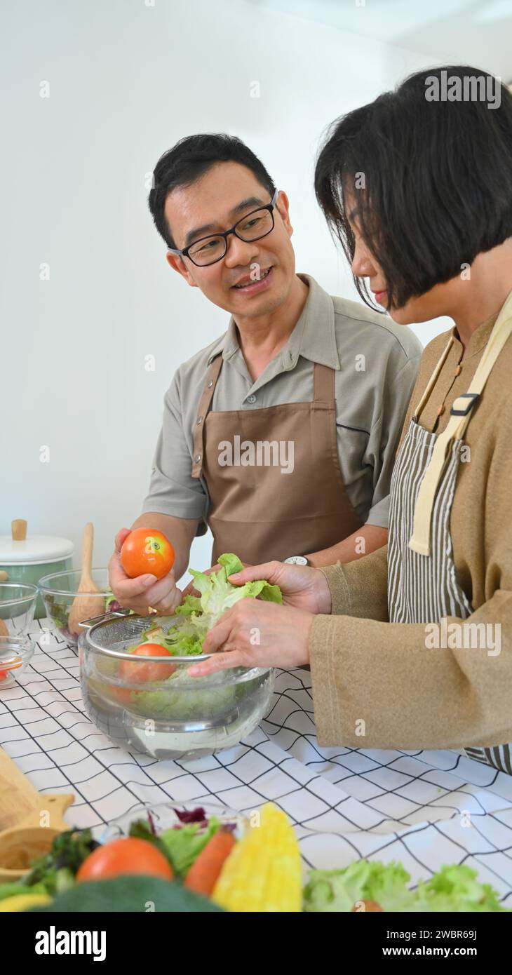 Happy senior couple having conversation while cooking healthy vegan ...