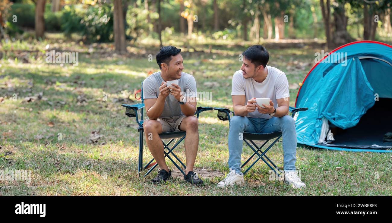 Gay LGBTQIA couple sitting on picnic chair drinking tea and coffee ...