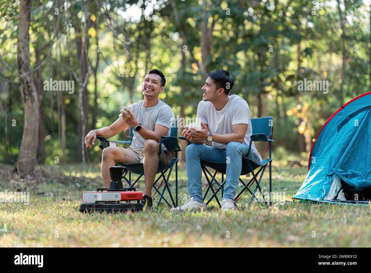 Gay LGBTQIA couple sitting on picnic chair drinking tea and coffee ...