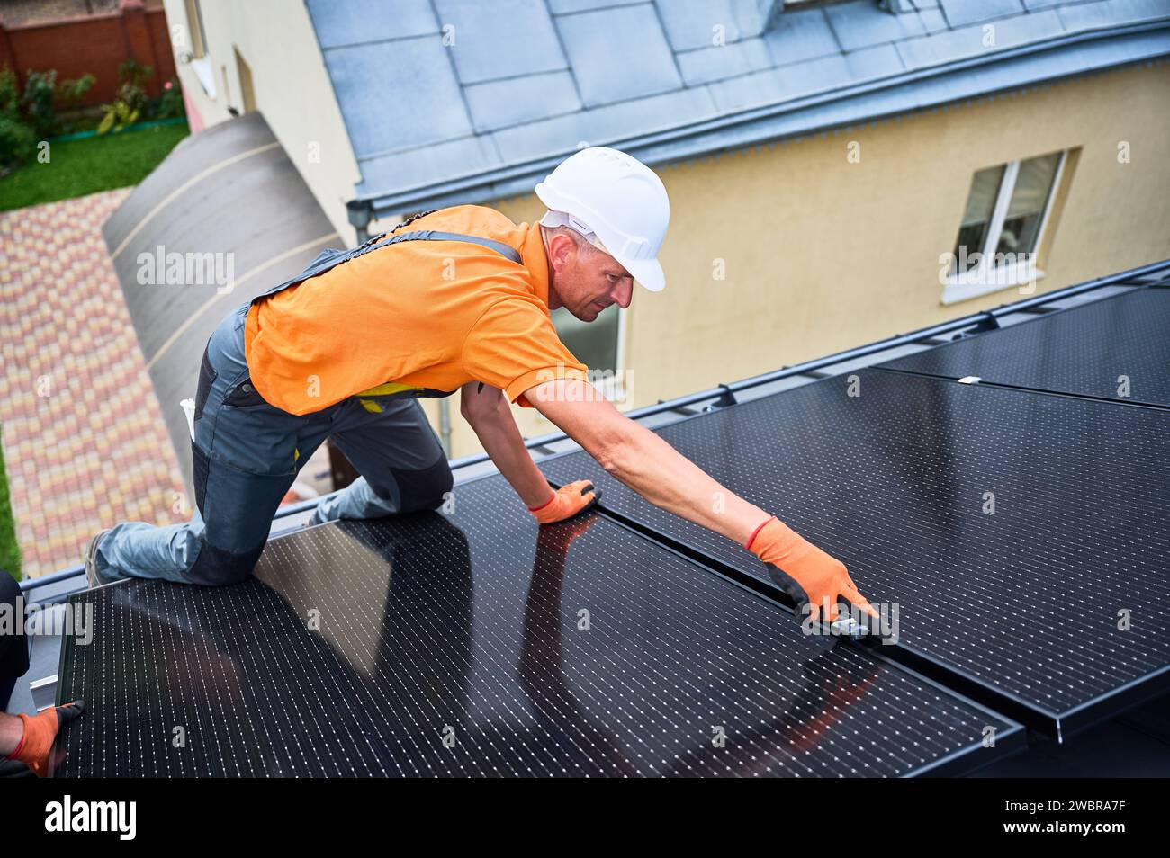 Worker building solar panel system on rooftop of house. Man engineer in ...
