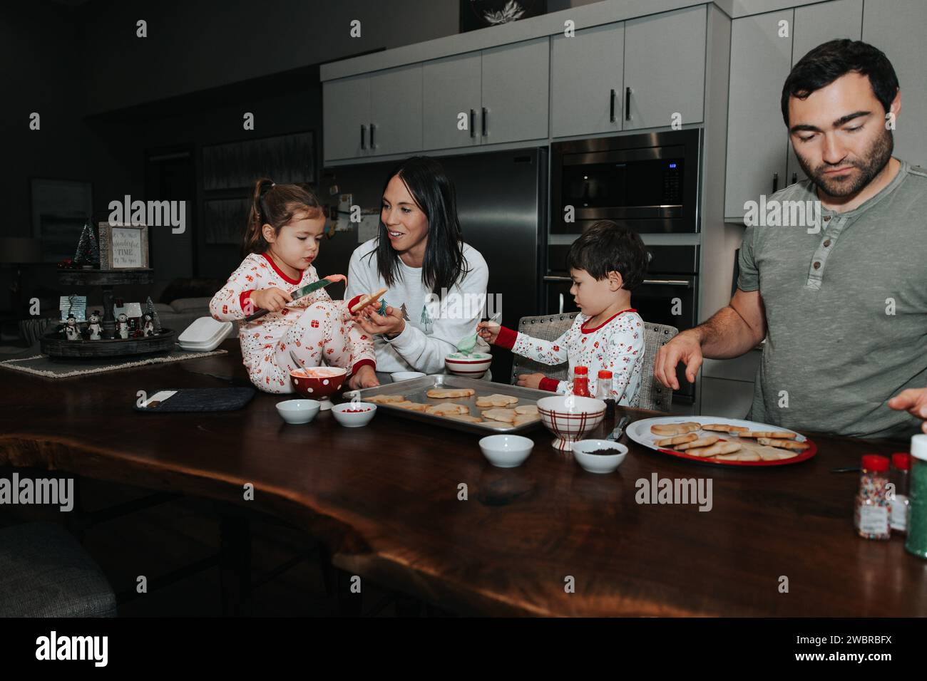 Family decorates christmas cookies in the kitchen happily Stock Photo ...
