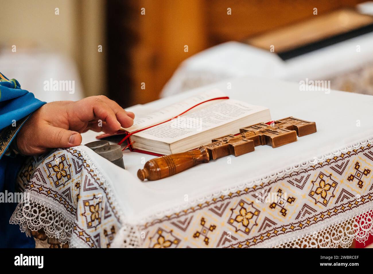 The priest's hand is on the Bible, the cross is next to it, church ...