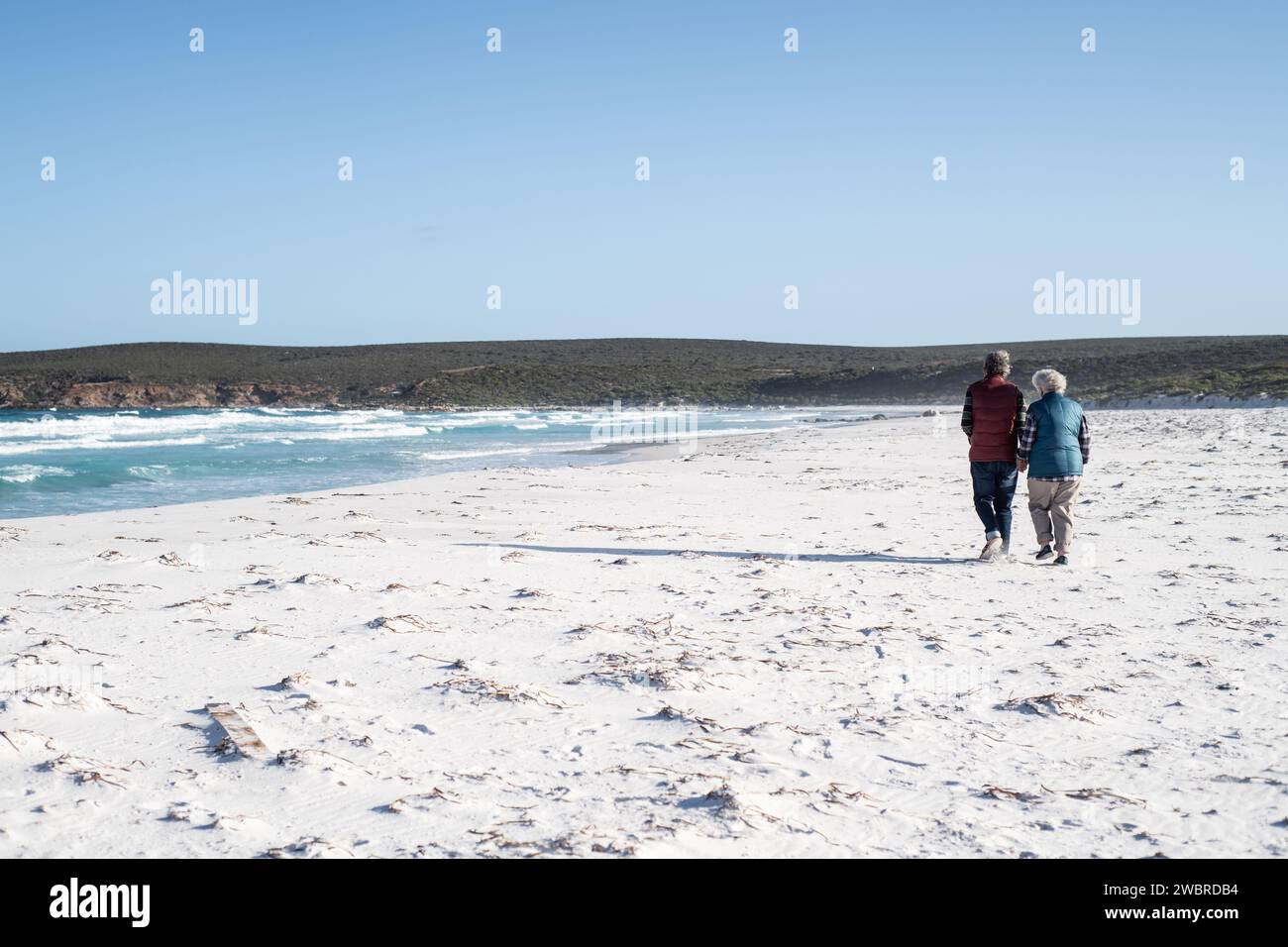 elderly retired healthy couple walk together along remote beach Stock ...