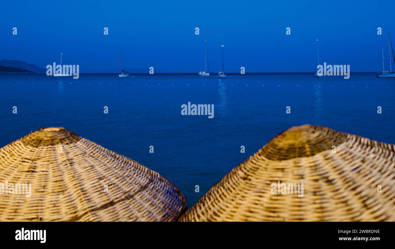 Aegean and Mediterranean coasts at sunset. Wicker umbrellas and sun ...