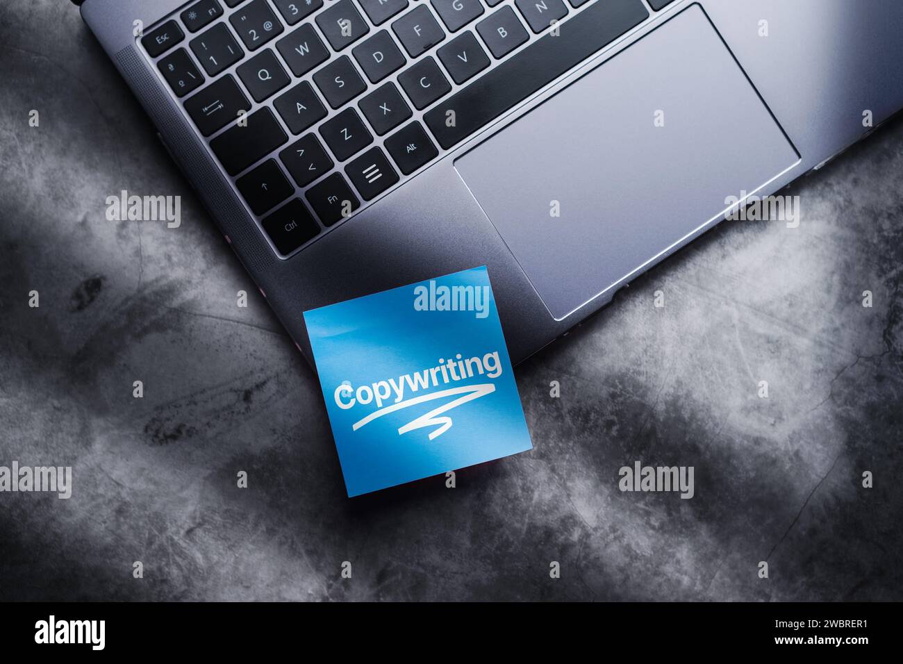 Copywriting word writen on a blue post it resting over laptop. Content ...