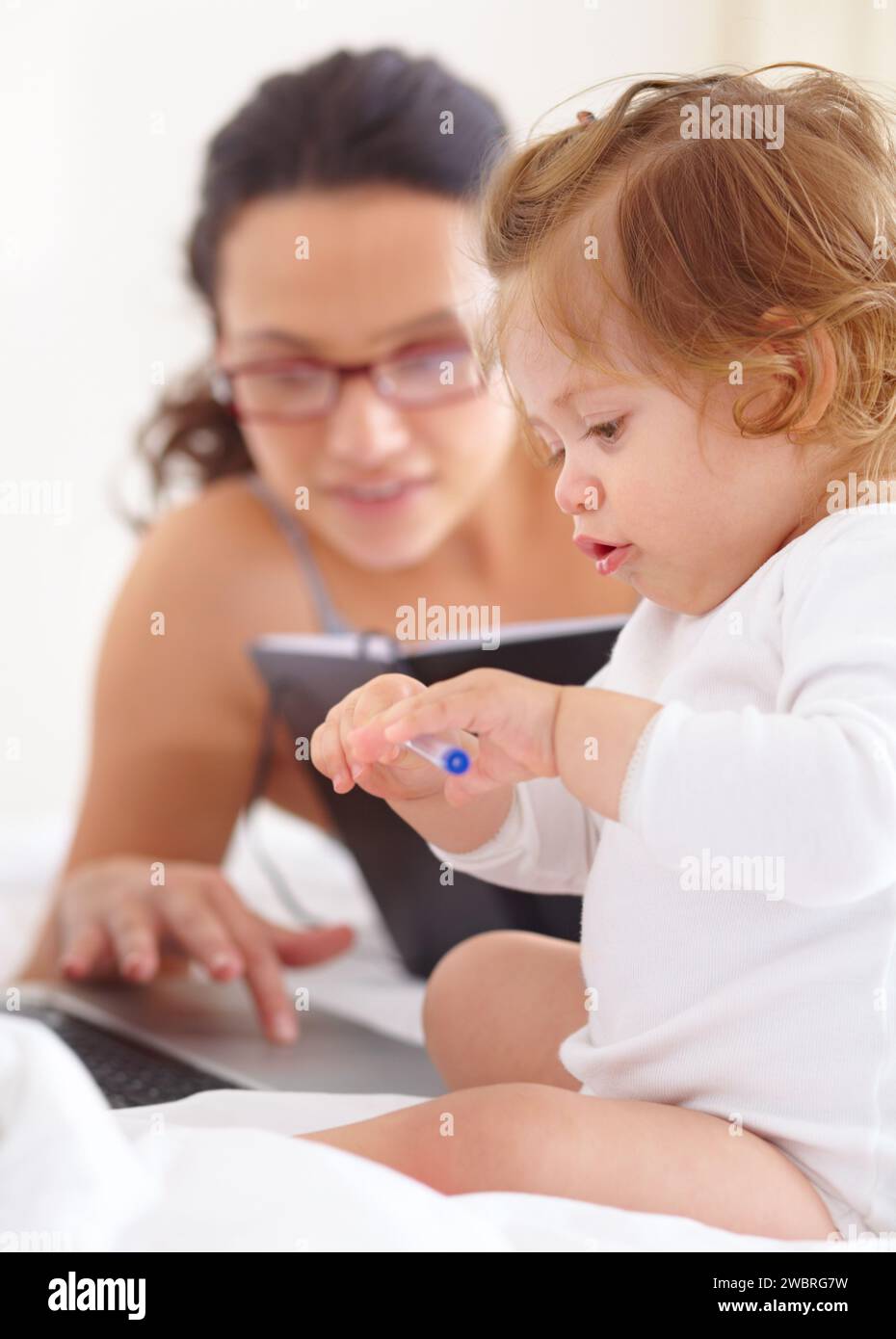 Mom, working and multitasking on laptop with baby in home for remote work or writing project ...
