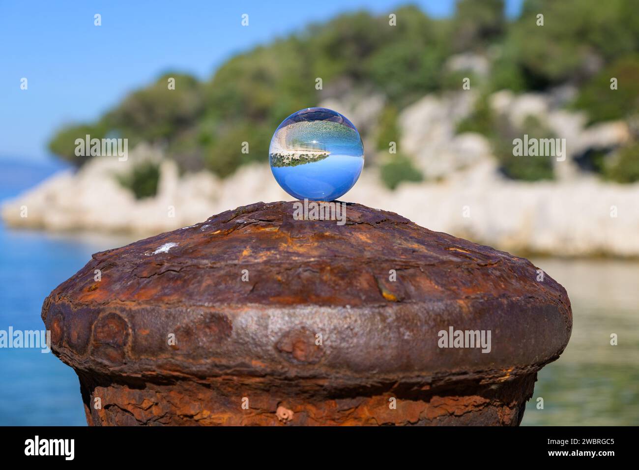 Glass ball lying on a rusty bollard, sunny day in autumn in Cres ...