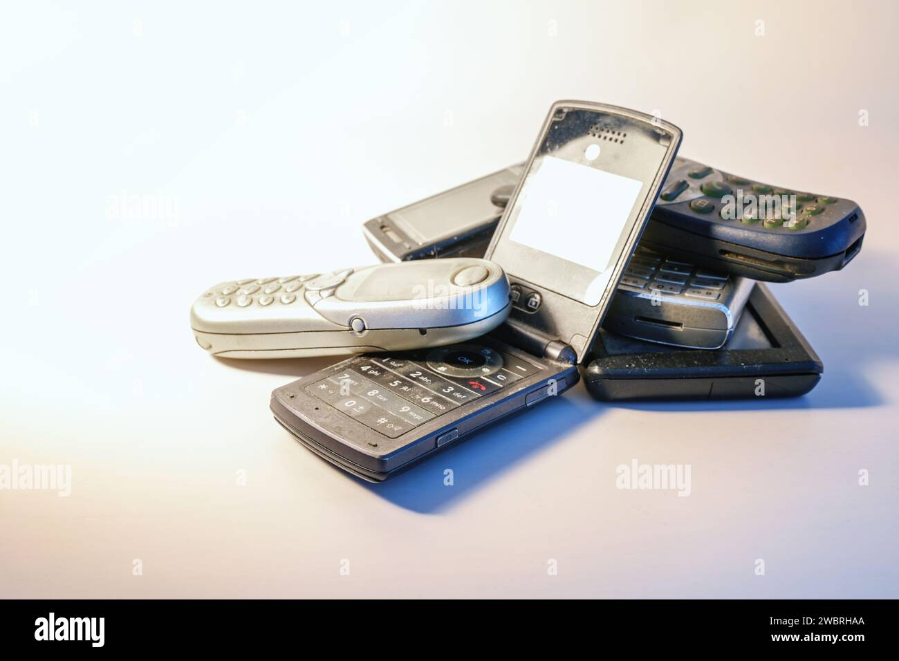 Dirty outdated cell phones in a small pile on a light background, short ...