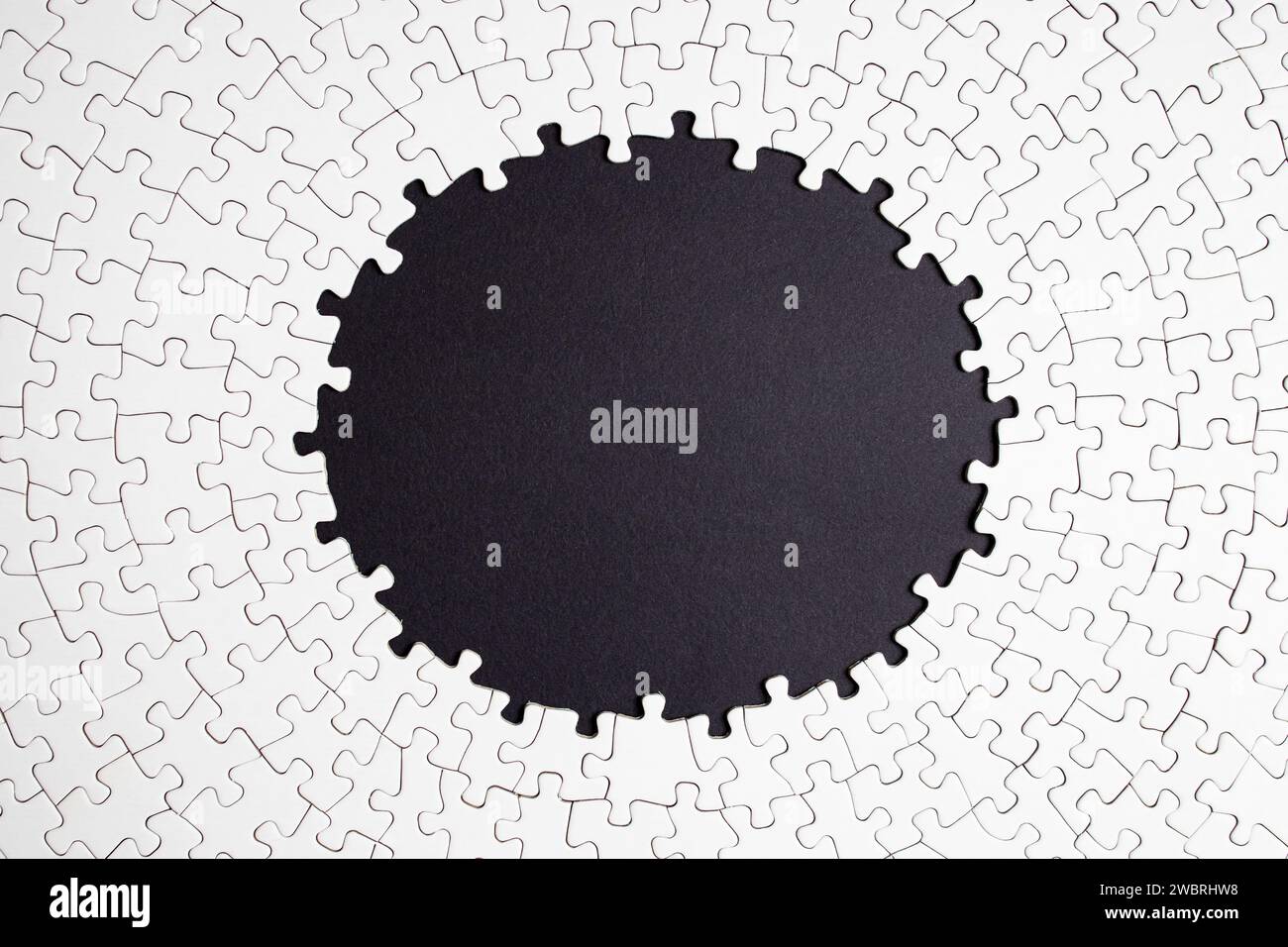 Plain white jigsaw puzzle on black color background, oval shaped frame ...