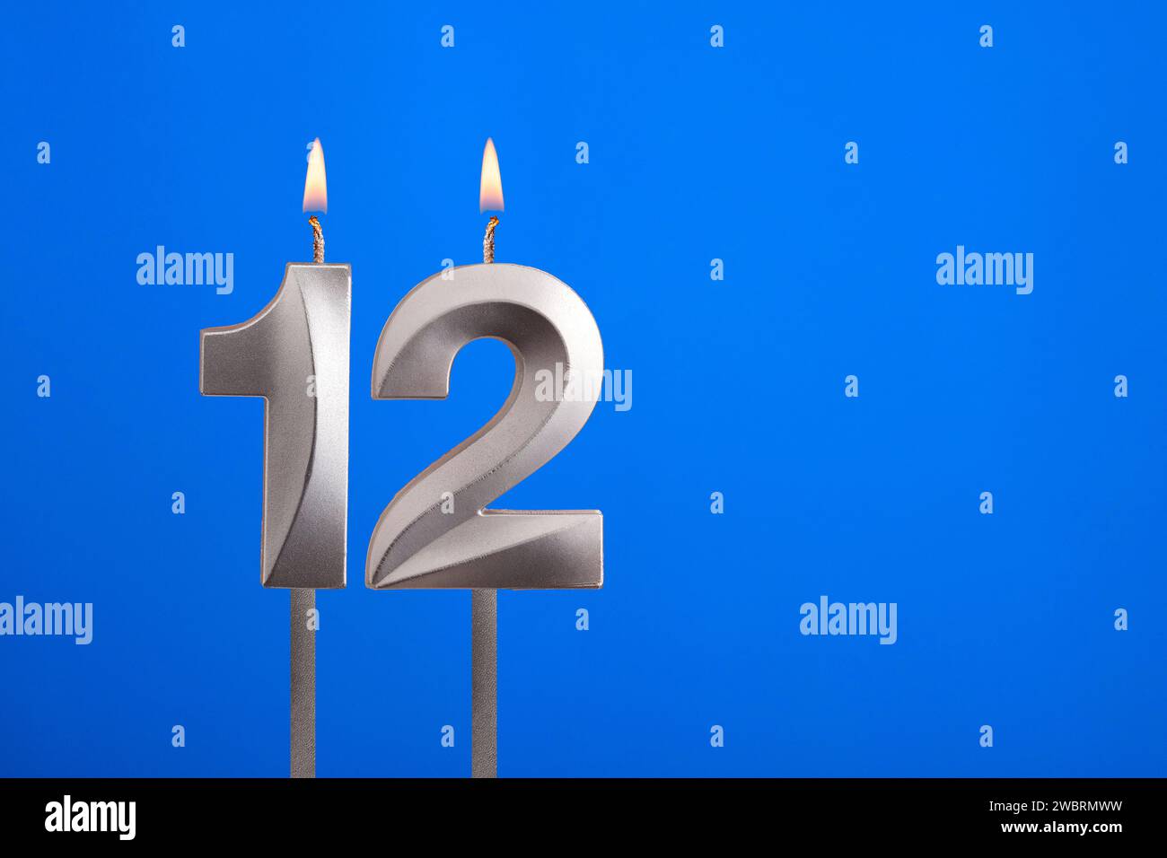 Birthday number 12 - Candle lit on blue background Stock Photo - Alamy