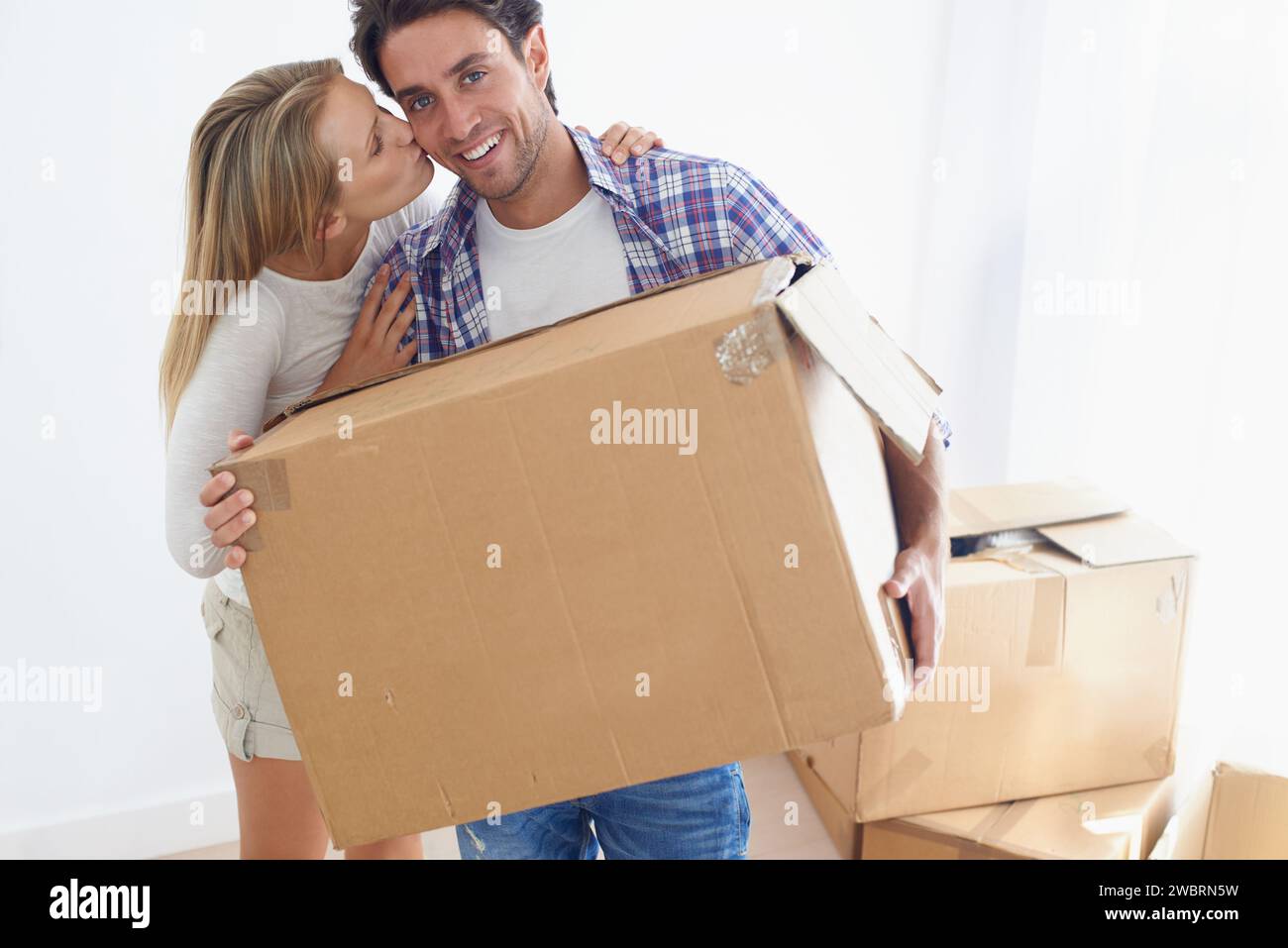 Couple, boxes and smile with kiss for real estate, new home or property investment with romance ...