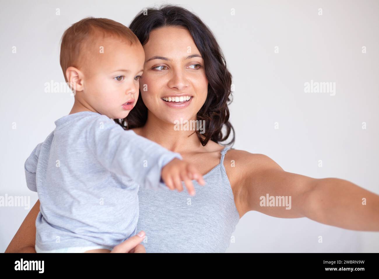 Mom holding toddler with smile, pointing and child care with support at home in morning. Happy ...