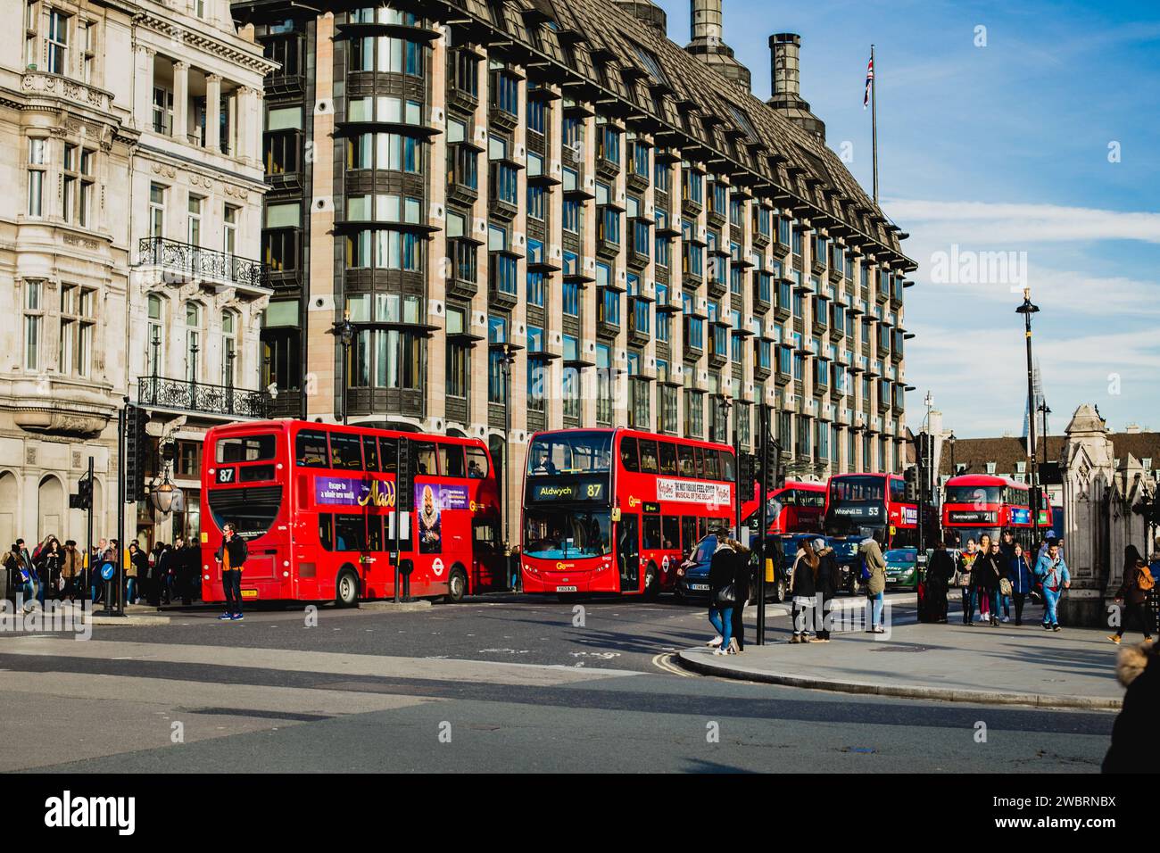 Five red urban buses are traveling one after the other on the streets ...