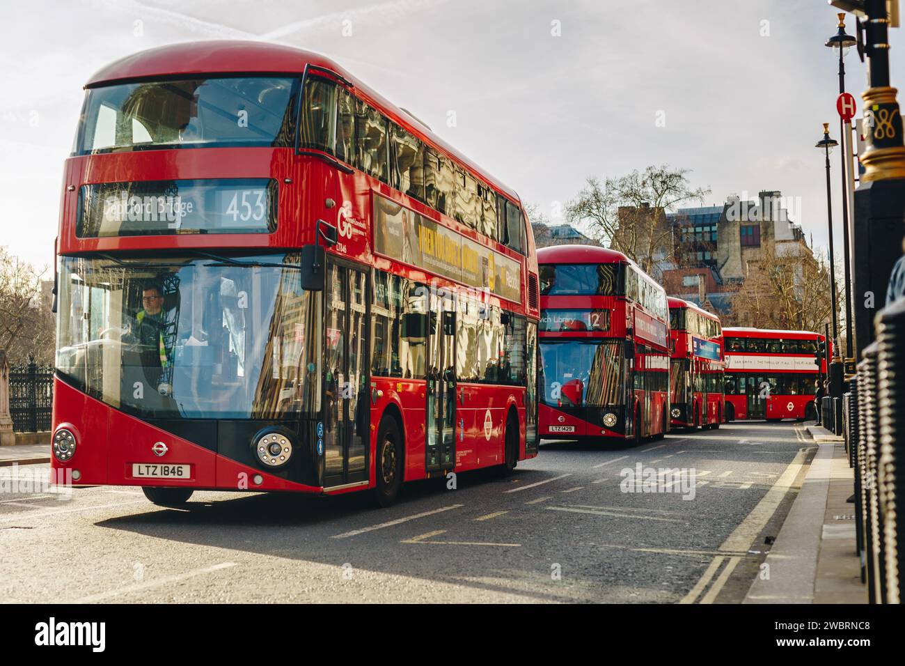 Four red urban buses are traveling one after the other on the streets ...