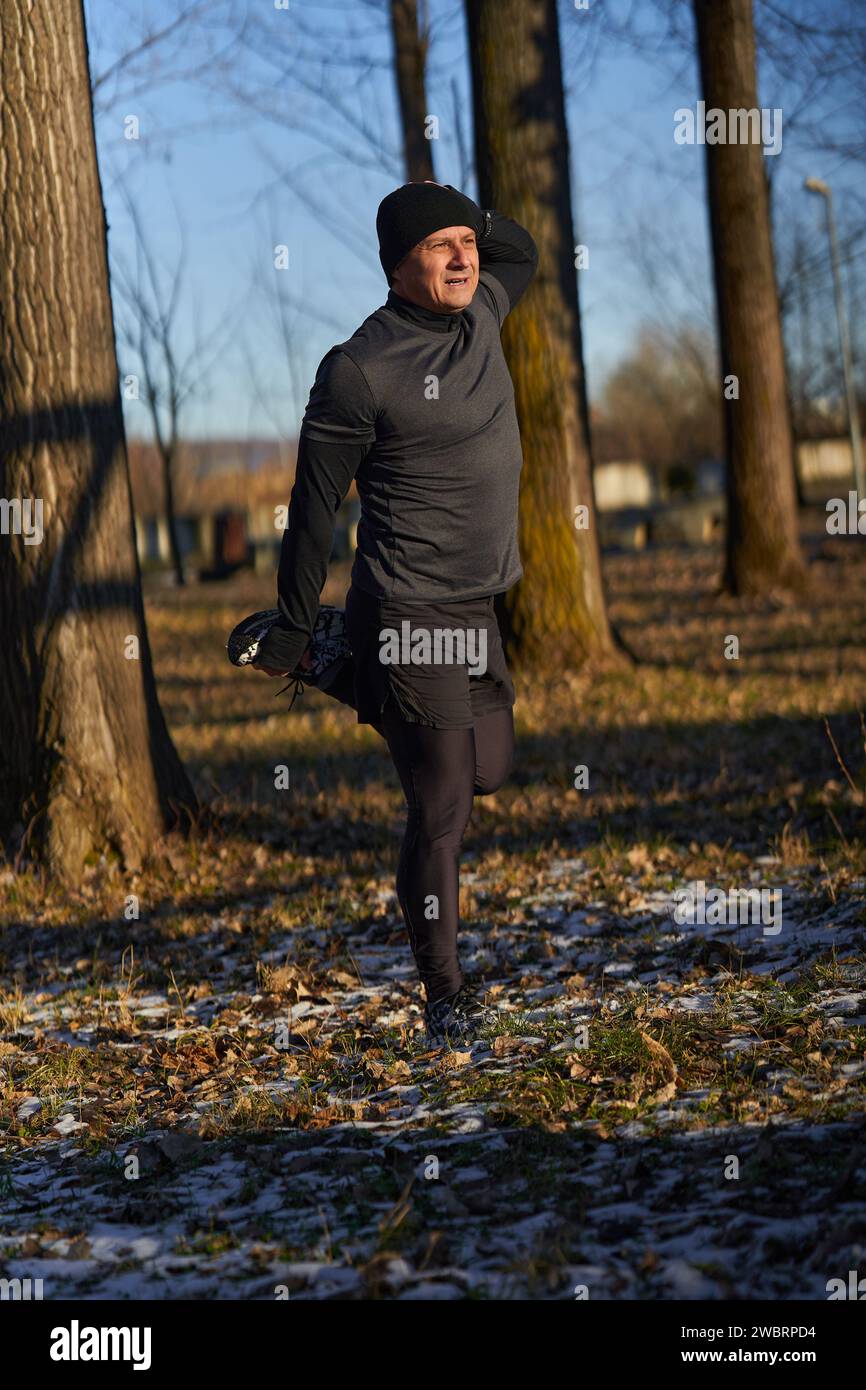 Mature recreational runner warming up and stretching before running in ...
