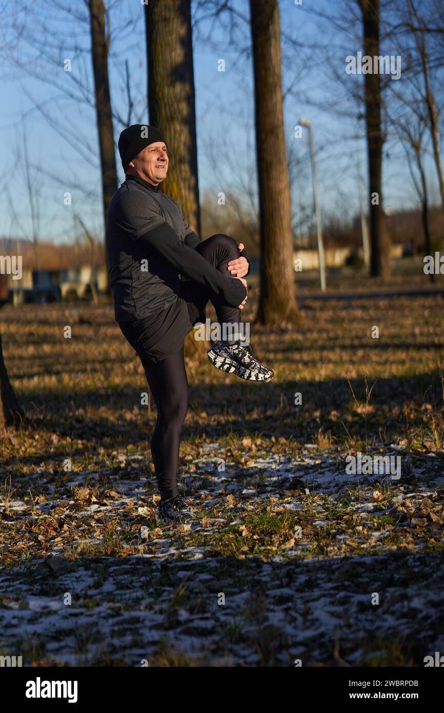 Mature recreational runner warming up and stretching before running in ...