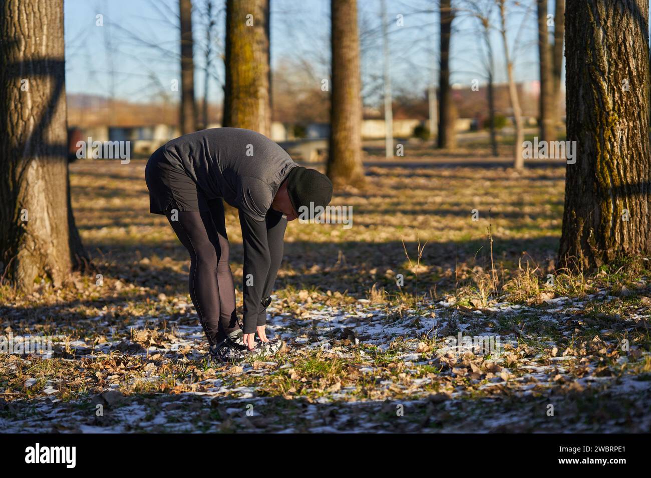 Mature recreational runner warming up and stretching before running in ...