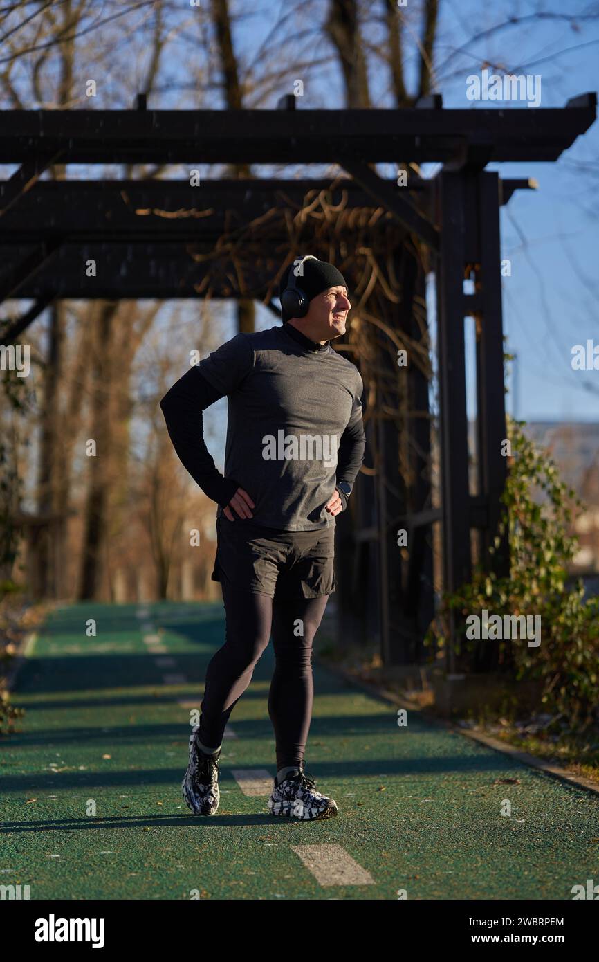 Mature recreational runner with headphones warming up and stretching ...