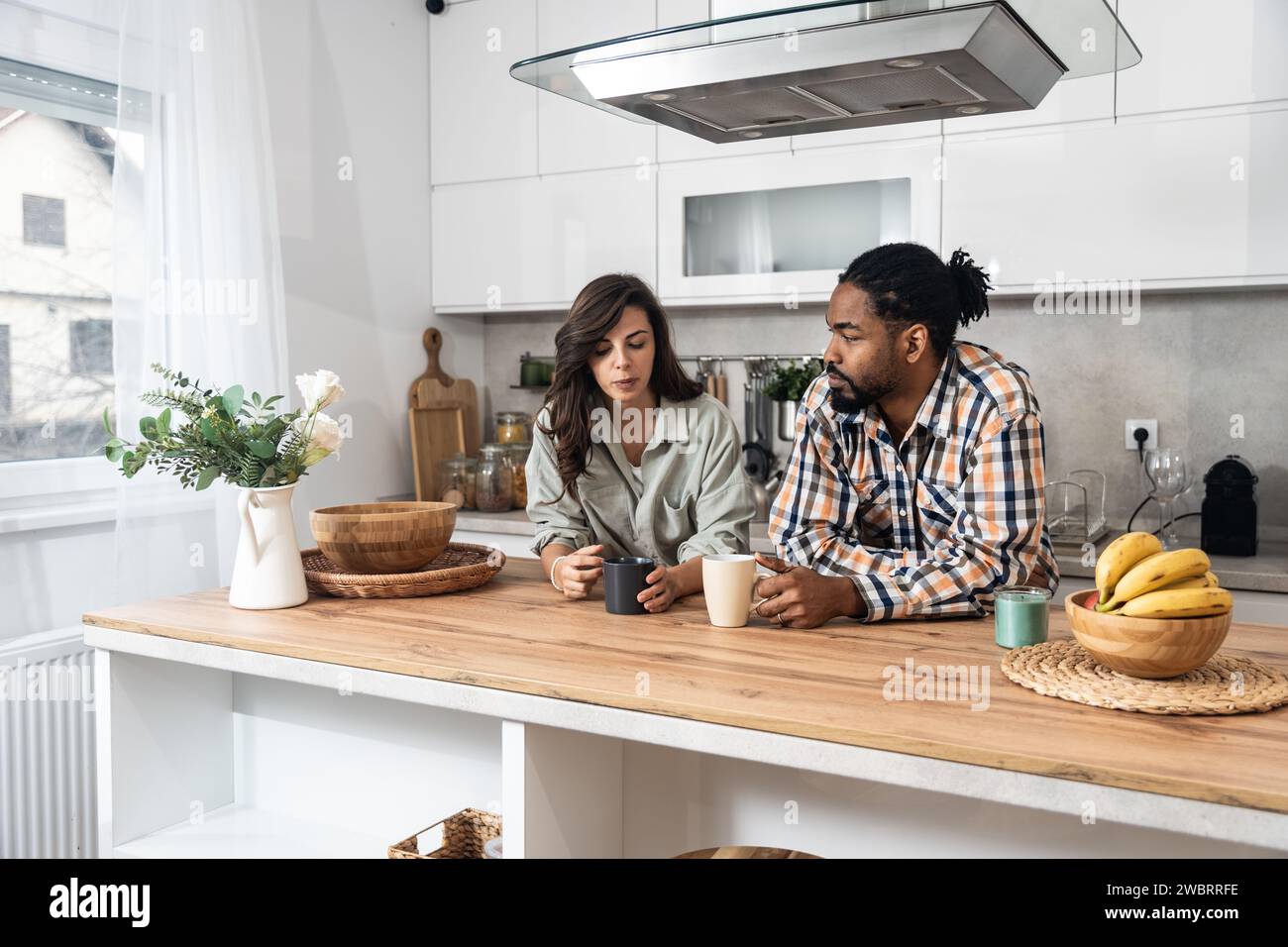 Young couple drinking coffee together in the kitchen on early morning ...