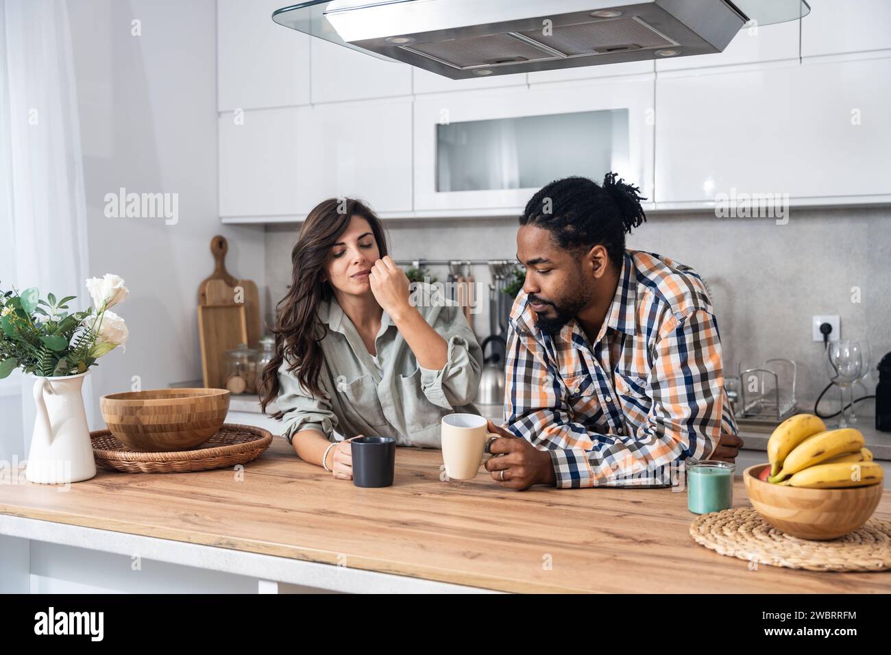 Young couple drinking coffee together in the kitchen on early morning ...