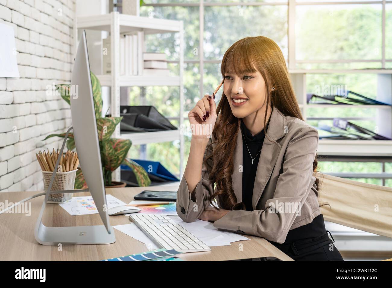 A young Asian graphic designer woman working in a creative dynamic ...