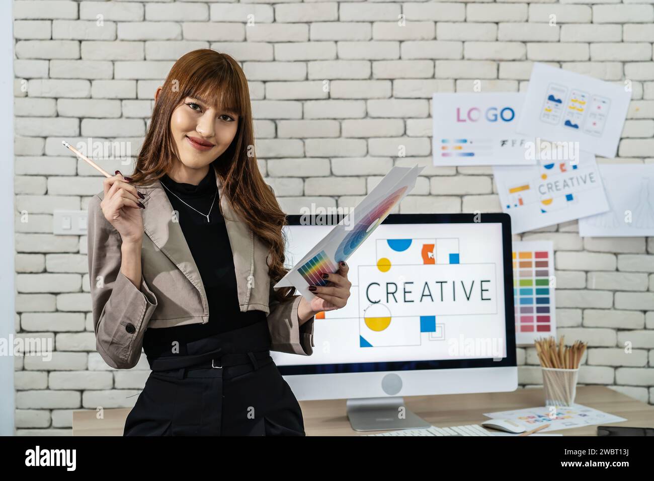 A young Asian graphic designer woman working in a creative dynamic ...