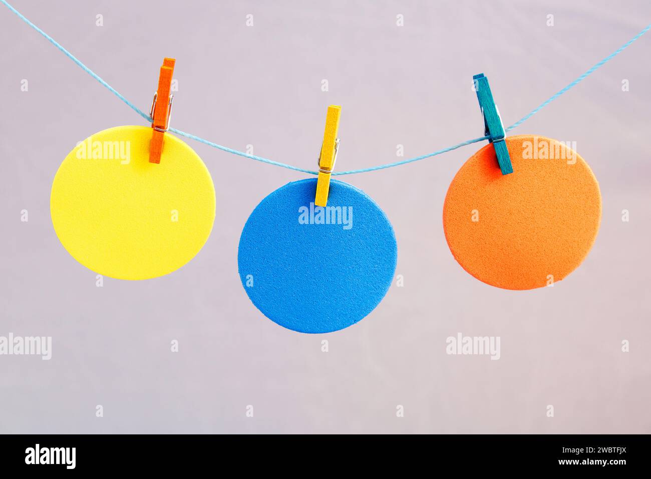 Colored circles attached to string with clothespins Stock Photo - Alamy
